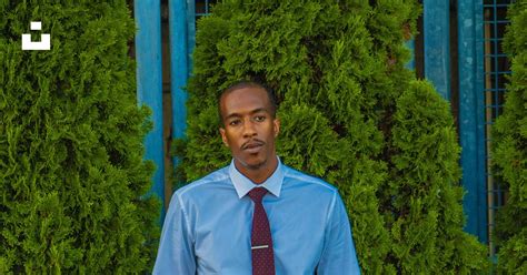 푸른 드레스 셔츠와 바지를 입은 남자가 녹색 잎이 달린 식물 근처에 있습니다 사진 Unsplash의 무료 디트로이트 이미지