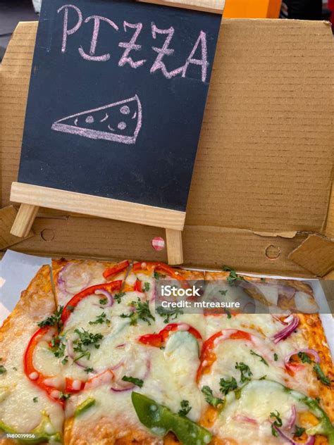 골판지 테이크 아웃 피자 상자에 얇게 썬 직사각형 채식 피자의 클로즈업 이미지 피자 슬라이스 그림이 있는 분필 보드 간판 빨강