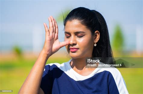 콧구멍 호흡이나 프라나야마 요가를 하거나 공원에서 눈을 감고 운동하는 인도 젊은 여성의 머리 사진을 닫습니다 평온함 이완 회춘의 개념 Pranayama에 대한 스톡 사진 및