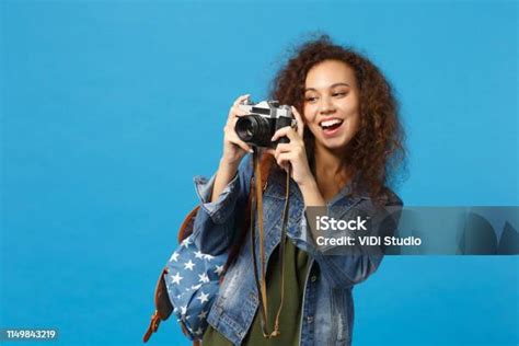 블루 벽 배경 스튜디오 초상화에 고립 된 데님 옷 배낭 홀드 카메라에 젊은 아프리카계 미국인 소녀 십 대 학생 고등학교 대학 대학 개념에서 교육 복사 공간을 모의 가방에