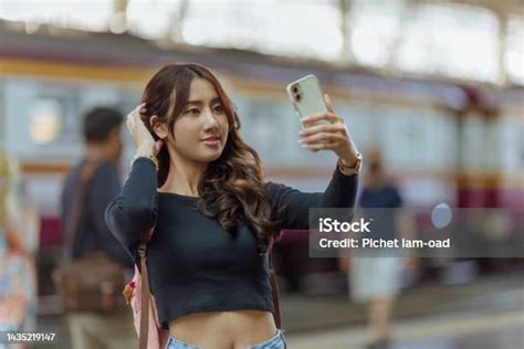 검은 긴 소매 티셔츠를 입고 기차 역 여행 개념 소셜 네트워크 기술 개념에 서있는 핸드폰을 들고 Shouder에 배낭을 들고