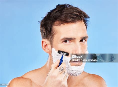 건강한 피부를 위한 위생 청소 및 자기 관리 루틴을 위한 남자의 얼굴 면도 및 면도기 초상화 웰빙 건강 및 파란색 스튜디오에 수염 거품이 있는 모델의 얼굴이 광고를 위해