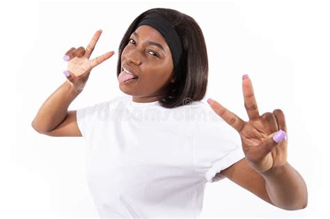 Portrait Of Young Woman Sticking Tongue And Making Rock Gesture Stock