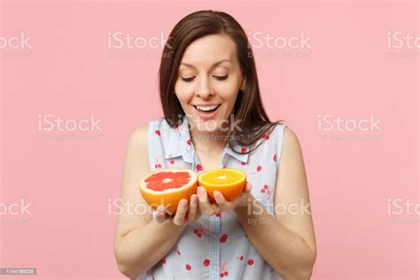 신선한 익은 자 몽 오렌지 과일 분홍색 파스텔 벽 배경에 고립의 Halfs를 들고 여름 옷에 흥분 젊은 여자 사람들은 생생한 라이프 스타일 휴식 휴가 개념입니다 복사 공간을