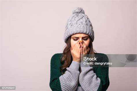 회색 스웨터 모자 스카프 재채기 또는 기침에 젊은 여자 회색 배경에 고립 된 손바닥으로 입을 덮고 건강 한 라이프 스타일 아픈 질병 치료 추운 계절 개념 가을에 대한 스톡