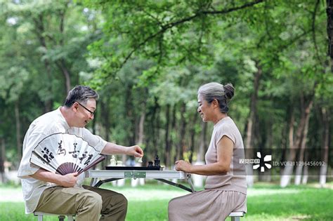 幸福的老年夫妇在公园下棋图片素材
