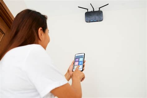 Premium Photo Housewife Setting Wi Fi Router Hanging On Wall Via Application On Smartphone