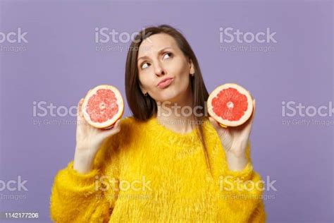 모피 스웨터 보라색 파스텔 배경에 고립 된 신선한 잘 익은 자 몽의 Halfs을 들고 찾고 젊은 여자를 의아해 사람들은 생생한 라이프 스타일 휴식 휴가 개념입니다 복사