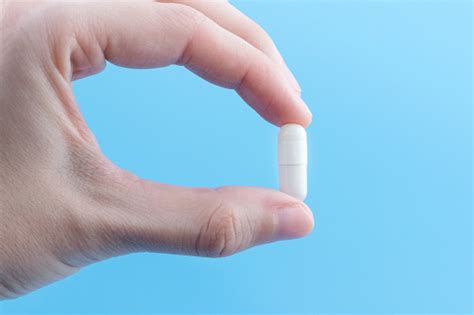 한 여성의 손이 파란색 배경에 캡슐클로즈업을 들고 있다 치료 의학 약물 알약 비타민 보충제 개념 간호사에 대한 스톡 사진 및 기타 이미지 Istock