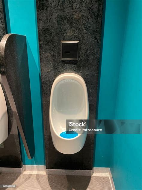 공중 화장실 화장실의 소변기 클로즈업 이미지 파란색 Pvc가 있는 흰색 세라믹 소변기 그릇에 담긴 향기로운 소변기 스크린 배경 스플래시 백 벽 내부에 배수구와 배수구가 있는