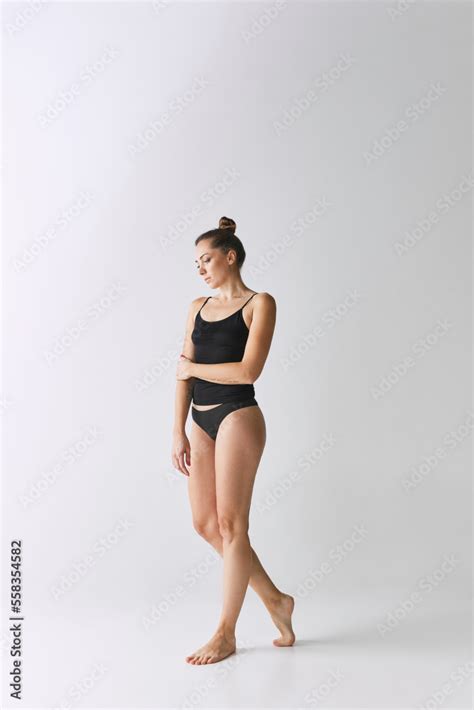 Full Length Portrait Of Slim Beautiful Mature Woman Posing In Black Underwear Over Grey Studio