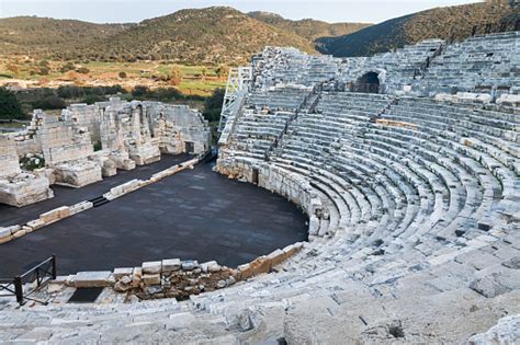 오래된 그리스 원형 극장과 먼 언덕이있는 햇볕이 잘 드는 지중해 풍경이있는 역사적인 파타 라 도시의 고대 유적 여름 터키 휴가의 역사와 모험 Lycian Way 안탈리아
