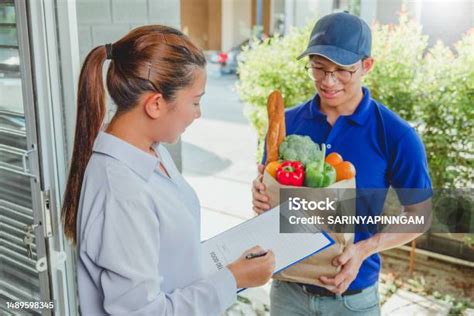 음식 배달 개념 아시아 여성은 전문 배달원 우체부로부터 음식 과일 채소 배달 가방을 손으로 받아들이고 식료품 배달을 표현합니다 25 29세에 대한 스톡 사진 및 기타 이미지