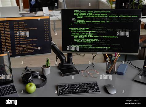 Still Life Shot Of Programmer Work Desk With Headphones And Multiple Computers Showing Lines Of