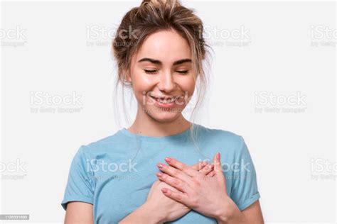 친절 한 젊은 여자의 솔직 한 초상화 웃 고 흰색 배경 위에 고립 된 파란 T 셔츠를 입고 닫힌 눈으로 가슴에 두 손바닥을 유지 합니다 사람 감정 느낌과 신체 언어 개념