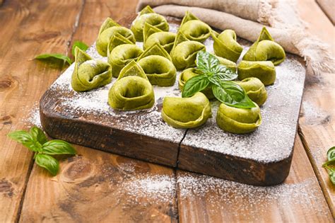 토르텔리니 E 토르텔로니 전형적인 요리 에밀리아 이탈리아 수제 생 이탈리아 어 토르텔로니와 나무 배경에 녹색 페스토 재료와 음식 배경 높은 각도 보기 공간을 복사합니다 0