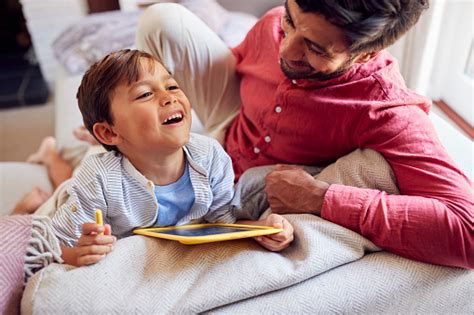 아버지와 아들은 라운지의 소파에서 집에서 디지털 태블릿 또는 전자 장난감을 함께 가지고 노고 있다 아들에 대한 스톡 사진 및 기타 이미지 Istock