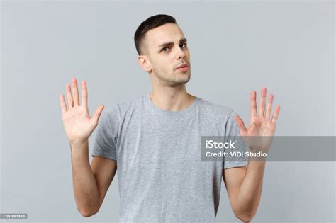 캐주얼 한 옷 카메라를 찾고에 당황 젊은 남자의 초상화 스튜디오에서 회색 벽 배경에 고립 된 손바닥을 보여주는 상승 손 사람들은 진심으로 감정 라이프 스타일 개념입니다 복사