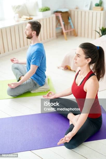 심각한 진정 고요한 젊은 부부 운동 매트에서 로터스 위치에 앉아서 Mudra 집에서 명상에 집중 하는 동안에 손을 잡고 건강한