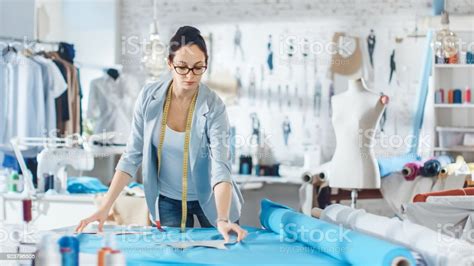 아름 다운 여성 패션 디자이너 직물의 조각에 그립니다 그녀는 밝은 다채로운 스튜디오에서 작품 다양 한 의류 직물 및 스케치의 전체 바느질하기에 대한 스톡 사진 및 기타
