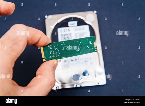 Man Holding NVME PCIE Fast Ssd Flash Memory Disk Drive With Old HDD Platter Hard Disk Drive In