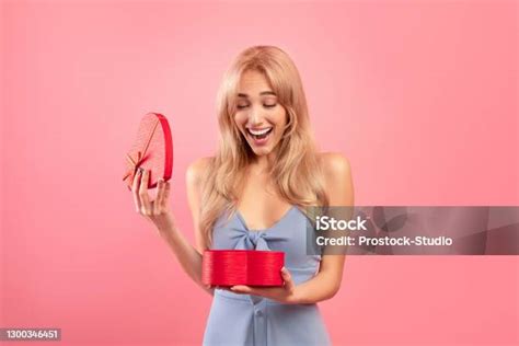 핑크 스튜디오 배경 위에 발렌타인 선물과 빨간 하트 모양의 상자를 여는 흥분 밀레니엄 여성 3월에 대한 스톡 사진 및 기타