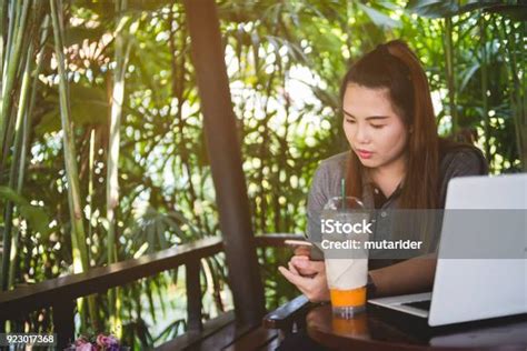 사용 하는 아름 다운 여자 스마트폰 노트북 및 갈색의 테이블에 아이스 티 갈색에 대한 스톡 사진 및 기타 이미지 갈색 노트북 노트북 사용하기 Istock