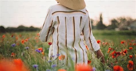 소박한 린넨 드레스를 입은 젊은 여성이 일몰 빛 아래 여름 초원 시골에서 양귀비와 수레국화 사이를 걷고 있다 시골의 느린 삶