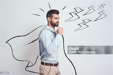 나는 충분히 강하다 자신감과 매력적인 젊은 남자는 번개 볼트의 그림과 회색 배경에 서 있는 동안 성공의 제스처를 보여주는 그려진 케이프를 입고 낙서 드로잉에 대한 스톡 사진
