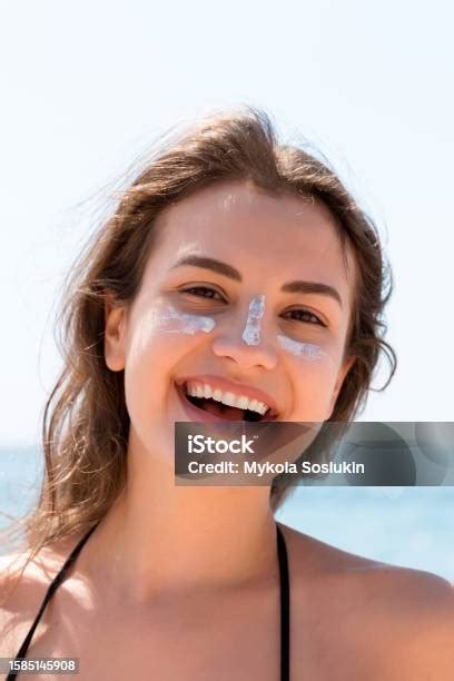 아름다운 젊은 여자가 바다 배경 위에 그녀의 얼굴에 선크림과 함께 카메라에 포즈를 취하고있다 25 29세에 대한 스톡 사진 및