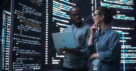 Portrait Of Two Diverse Developers Using Laptop Computer Discussing