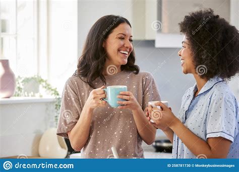 Loving Same Sex Female Couple Wearing Pyjamas Making Morning Pancakes In Kitchen At Home Stock