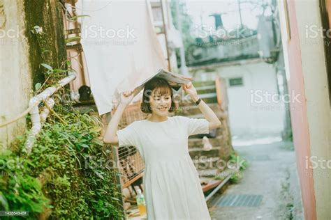 시골 근처의 오래된 마을에서 소책자를 읽으며 책을 생각하고 머리에 올려 놓는 젊은 아시아 여성 20 29세에 대한 스톡 사진 및 기타 이미지 Istock