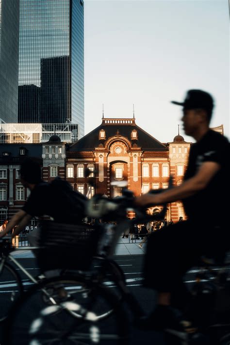 자전거를 타는 사람들이 현대 도시의 건물을 지나갑니다 사진 Unsplash의 무료 거리 사진 이미지