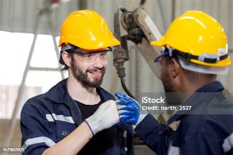 공장에서 자동 기계 로봇으로 함께 일하는 두 명의 엔지니어 남성 기술자 유지 보수 및 개선하면서 원격 산업 및 혁신 개념으로 로봇 및 제어의 Ai를 검사합니다 2명에 대한