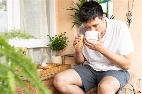 대나무 나무 도구로 말차 녹도 행사를 축하하고 손으로 만든 도자기 차완 그릇에 차를 가득 담은 냄새를 맡는 남자차센 털과 차사쿠