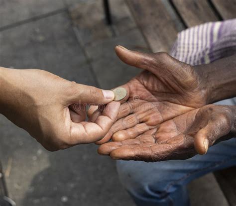 Close Up Of Hands One Giving Money To The Other Hand Of A Homeless Man