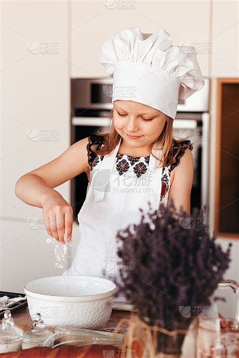 可爱的小女孩戴着白色厨师帽在厨房玩面粉