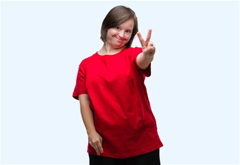 다운 증후군 승리 표시를 하 고 카메라에 윙크 하는 행복 한 얼굴로 웃 고 고립 된 배경 위에 젊은 성인 여자 번호 2입니다 긍정적인 감정 표현에 대한 스톡 사진 및 기타