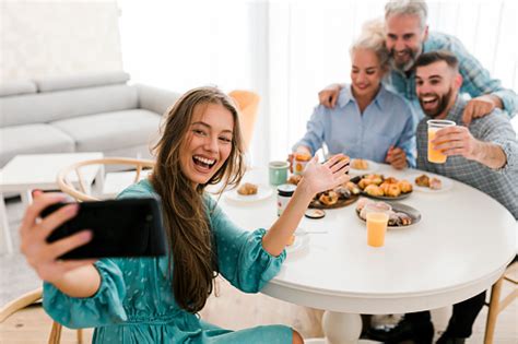 행복한 가족은 셀카를 찍고 실내에서 함께 식사를합니다 아침 식사 중에 식탁에 앉아 웃는 세대 가족 거실에서 함께 식사를 즐기는 행복한 쾌활한 가족 4 명에 대한 스톡 사진