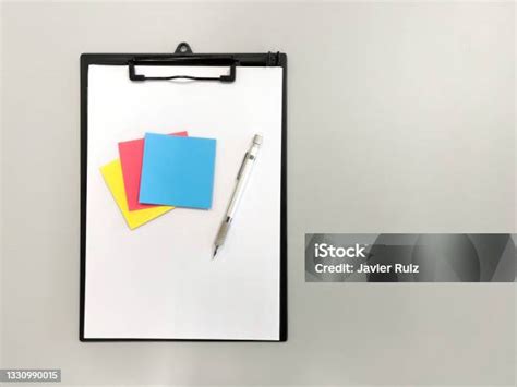 빈 종이와 금속 기계 연필과 회색 테이블에 여러 가지 색 메모 종이가있는 검은 클립 보드 폴더의 상단 보기 0명에 대한 스톡
