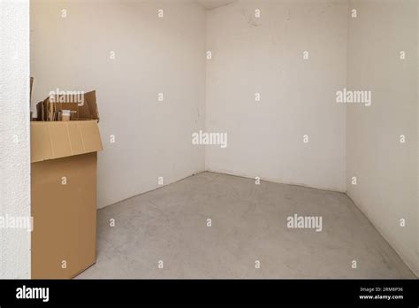 A Small Empty Storage Room With A Cardboard Box And Raw Concrete Floors
