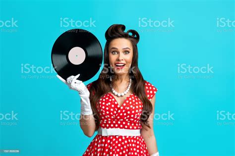 축음기 비닐 레코드를 들고 웃고 파란색 배경을 통해 카메라를보고 복고풍 드레스에 행복한 핀업 여자 축음기에 대한 스톡 사진 및 기타 이미지 Istock