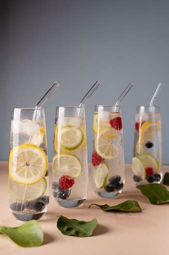 빨대가 달린 유리잔에 감귤류와 베리를 곁들인 상쾌한 탄산수를 우아하게 표현하여 미니멀한 배경 수직 배열 깔끔하고 깨끗한 여름의