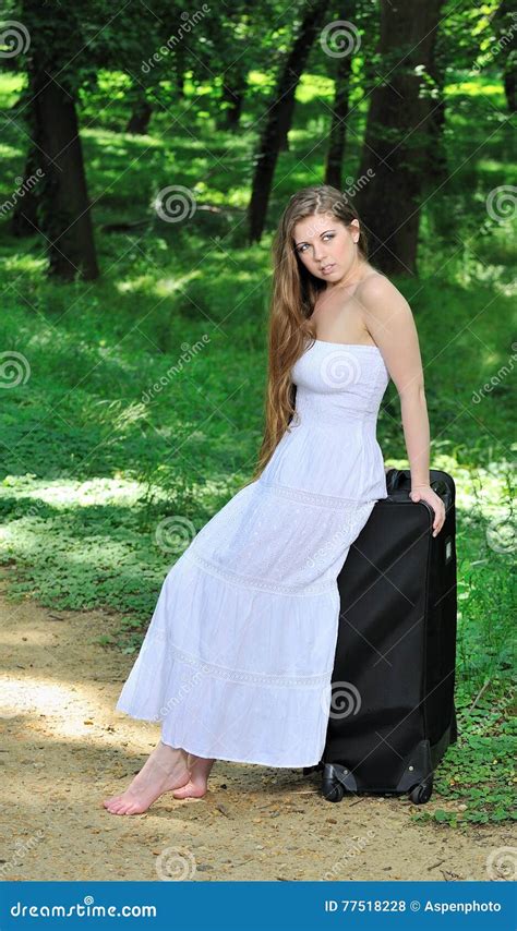 Сексуальная молодая женщина в Sundress ждет с чемоданом Стоковое Фото изображение