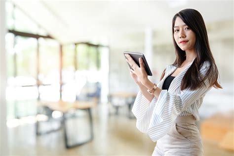 현대 사무실에 서있는 동안 디지털 태블릿을 들고 카메라를 보는 아름다운 아시아 사업가 20 24세에 대한 스톡 사진 및 기타 이미지 20 24세 경영자 긍정적인 감정