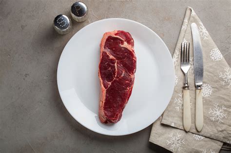 원시 쇠고기 오래 된 돌 배경에 빈티지 화이트 기구와 스테이크를 차 돌 박이 후추와 소금 테이블에 고기 조각 뉴욕 스테이크입니다 상위 뷰 갈비 음식에 대한 스톡 사진 및