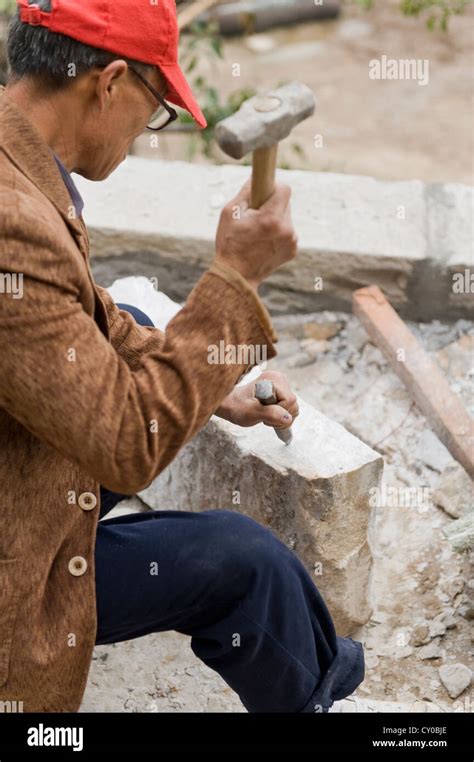 A Man Hammering A Chisel On Rocks At The San Huang Zhai Monastery On The Song Mountain China