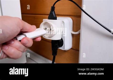 Overloaded Outlet With An Extension And Many Sockets Plugged In A Hand Plugging A Socket Into