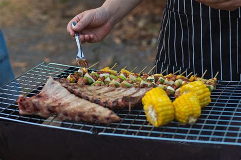바베큐 파티를 위한 고기와 꼬치 재료를 그릴에 올려 바베큐를 요리하고 오늘 밤 가족이 바베큐 파티에 참여할 수 있도록 준비합니다